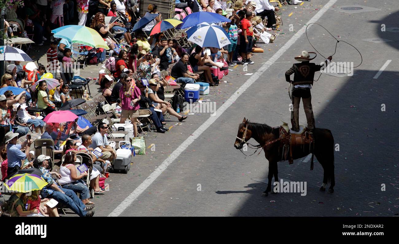 A charro performs rope tricks for parade goers during the Fiesta Battle ...