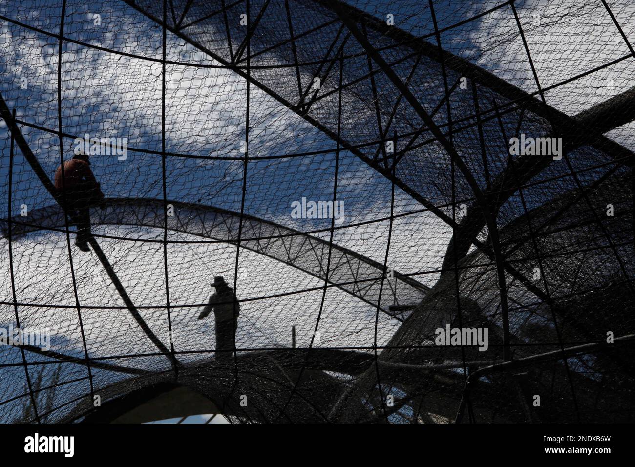 Workers build the wire structure of a dome that will shelter a ...
