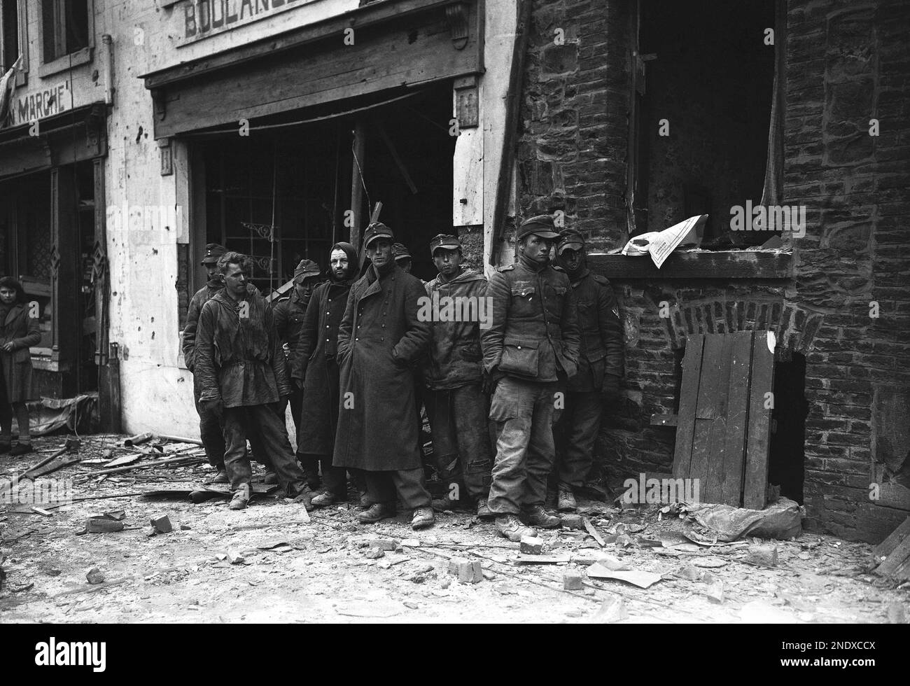 These German soldiers stand in the debris strewn street of Bastogne ...