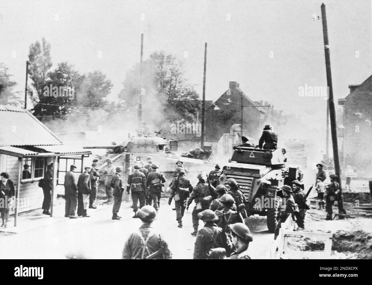 Canadian infantrymen with tanks and armored cars move through the town ...