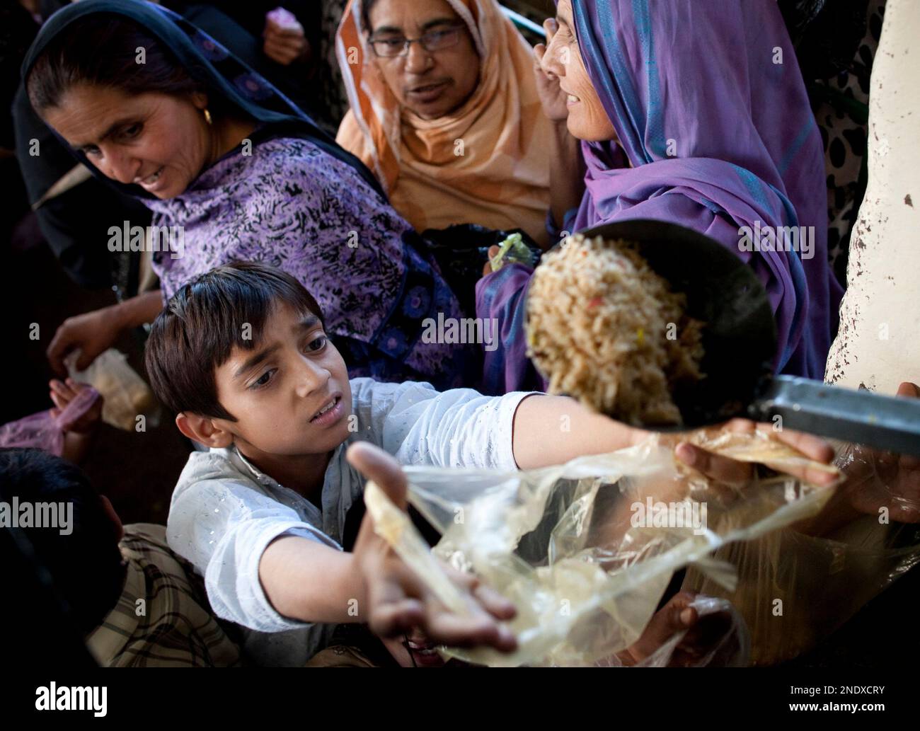 Pakistani children receive a ration of donated rice at the Sufi shrine ...