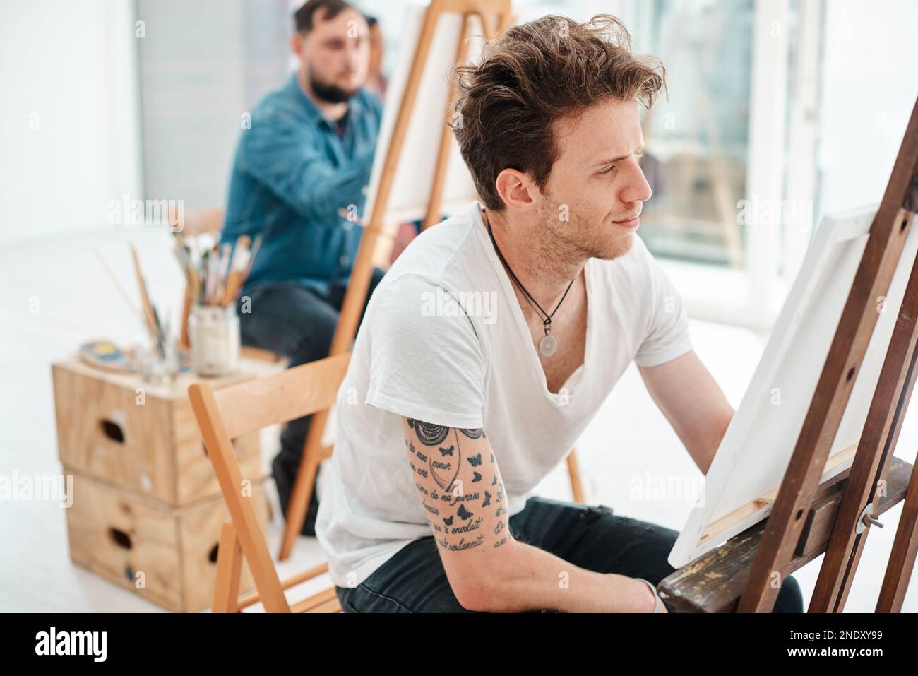 He is focused on his masterpiece. a handsome young artist sitting and ...