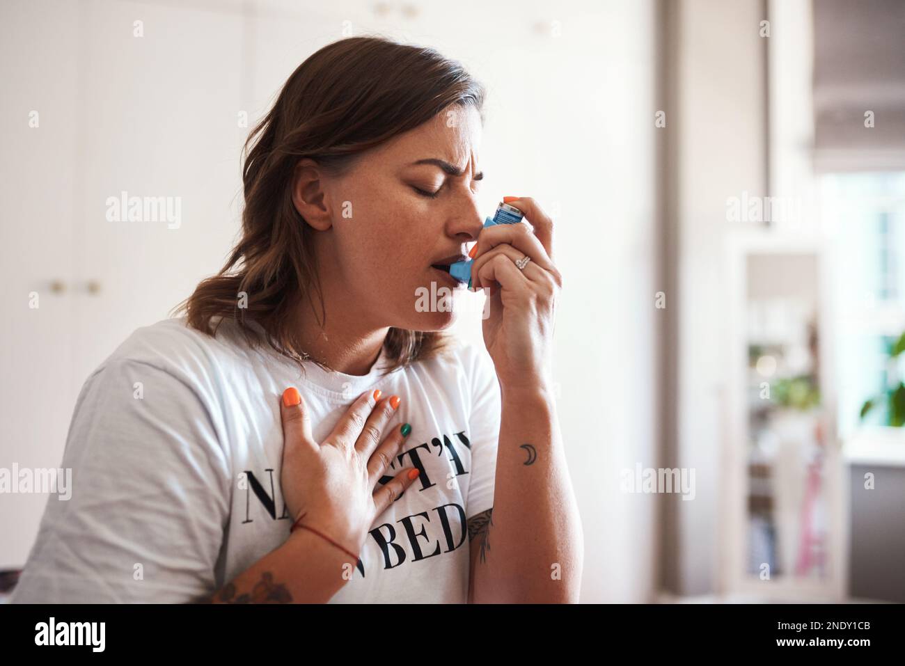 I cant breathe. a beautiful young woman using her asthma inhaler Stock ...