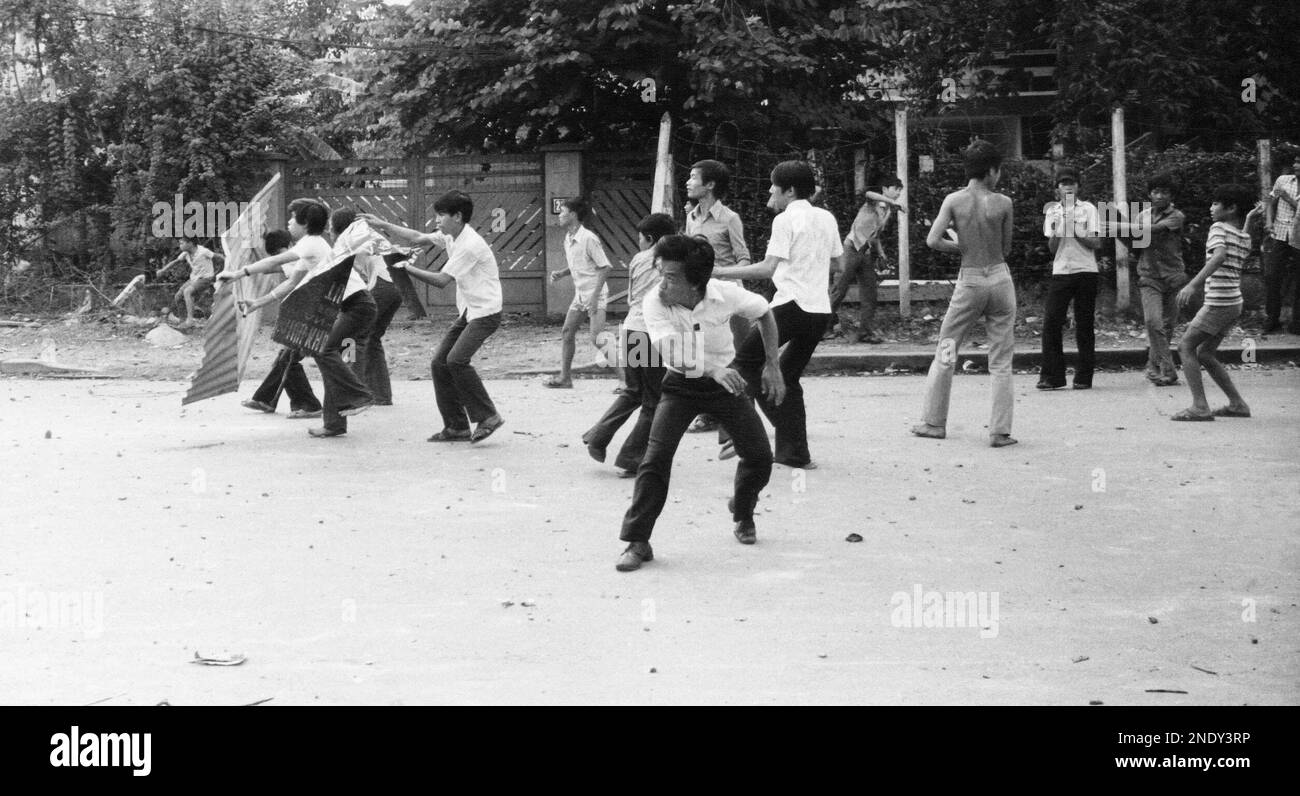 Rock throwing anti-government demonstrators, some hiding behind a ...