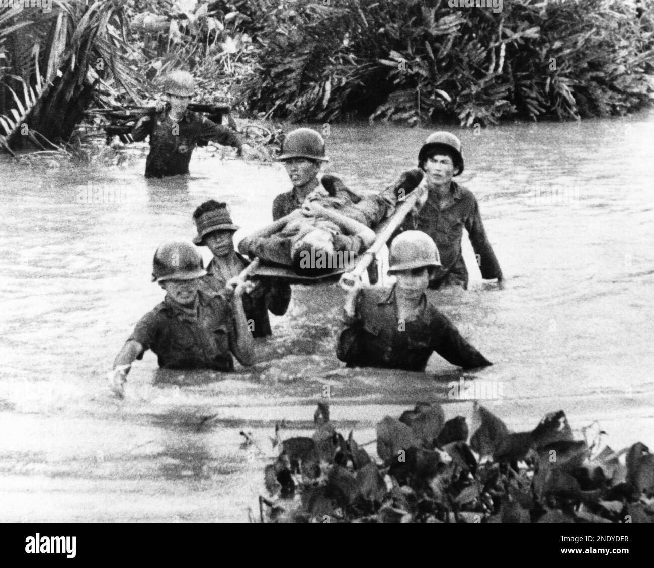 South Vietnamese soldiers carry a wounded soldier across a flooded ...