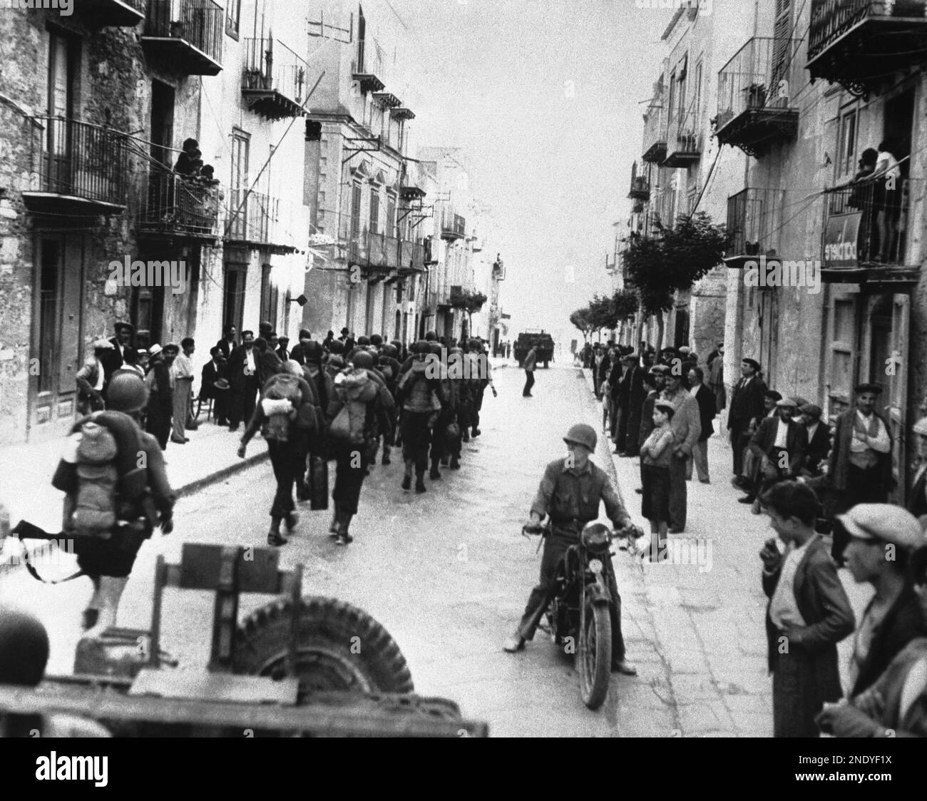 Allied troops march through a Sicilian town as the populace calmly ...