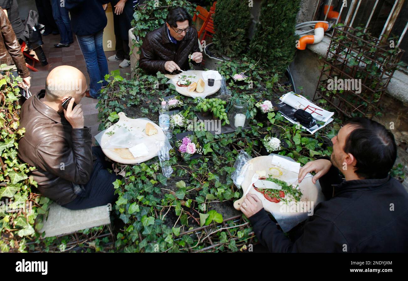 People eat on a wrought iron table with ivy growing all over the ...