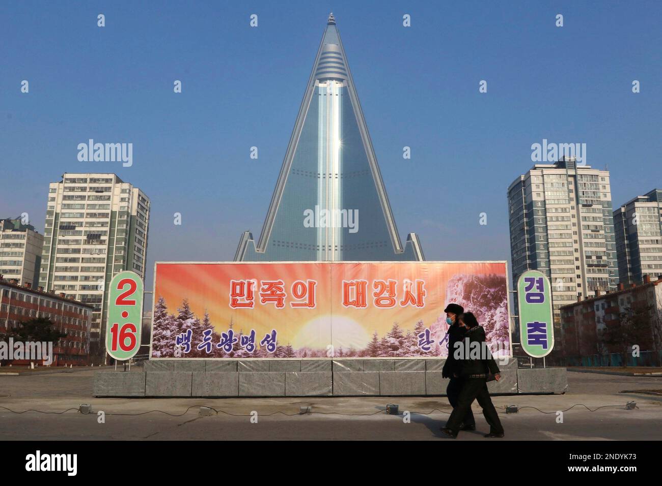 A man and a woman walk past a visual aid that reads, "Auspicious event ...
