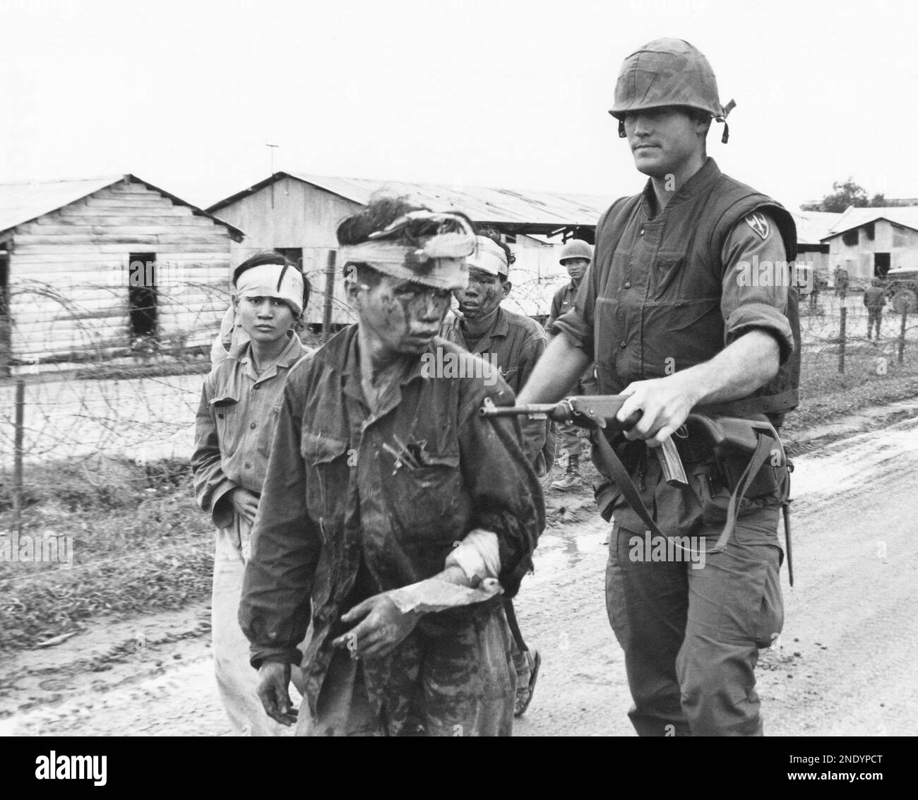 An American soldier uses his carbine to point the way for wounded Viet ...