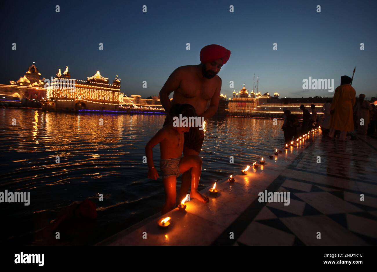 A Sikh devotee and his child emerge after taking a dip in the holy pond ...