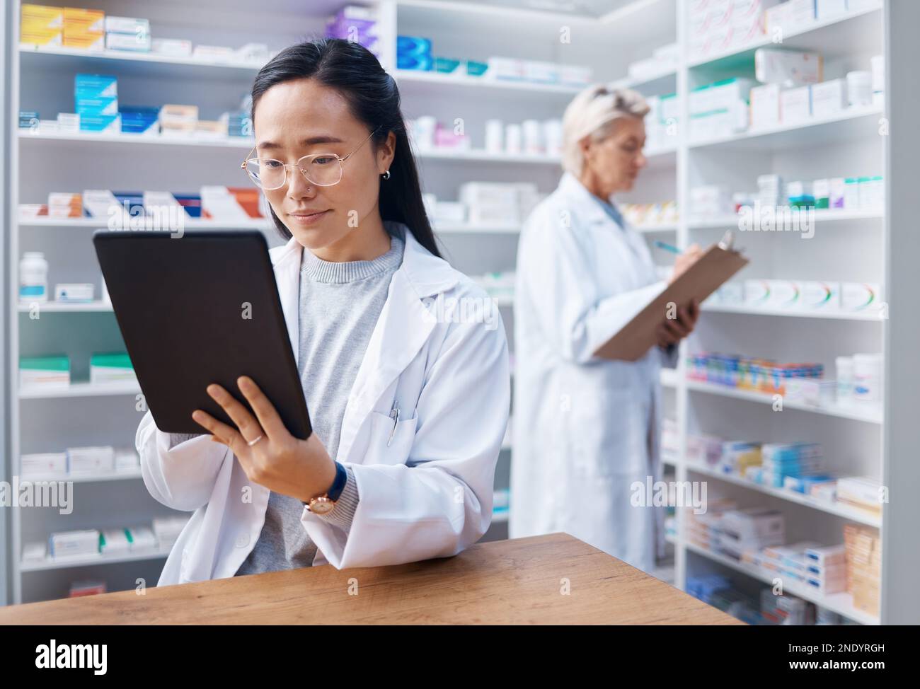 Tablet, Asian woman and pharmacist in pharmacy for healthcare or online ...