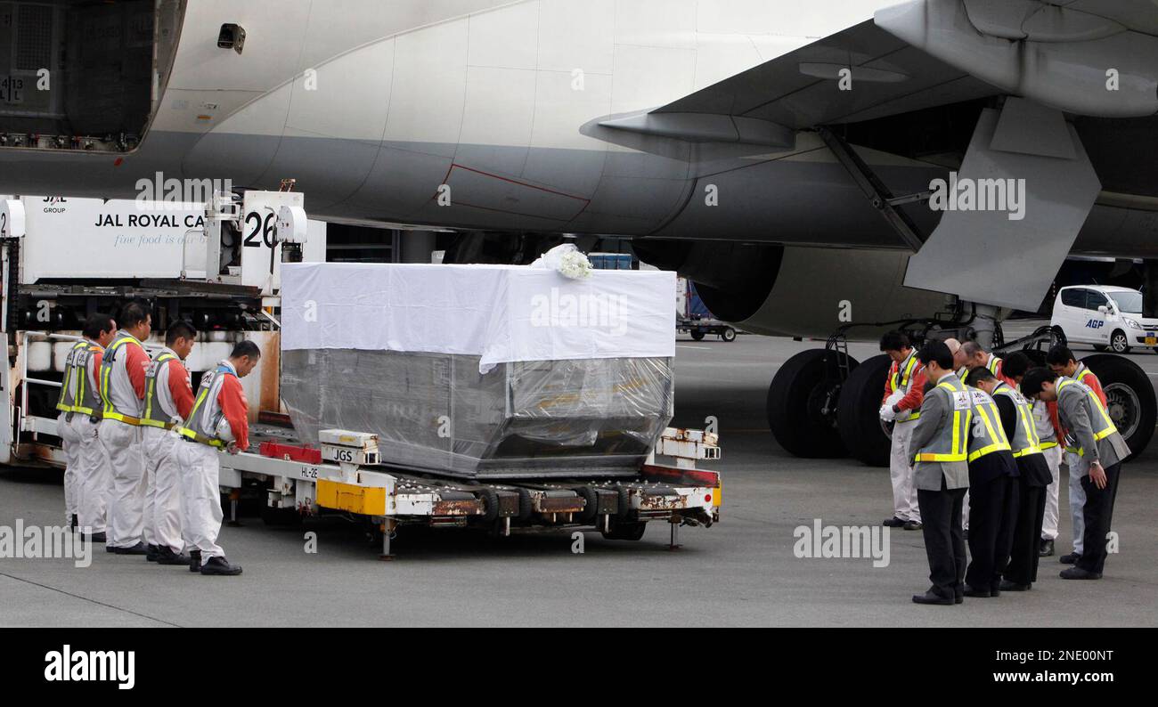 Airport ground crew bow to pay their respects as a container bearing ...