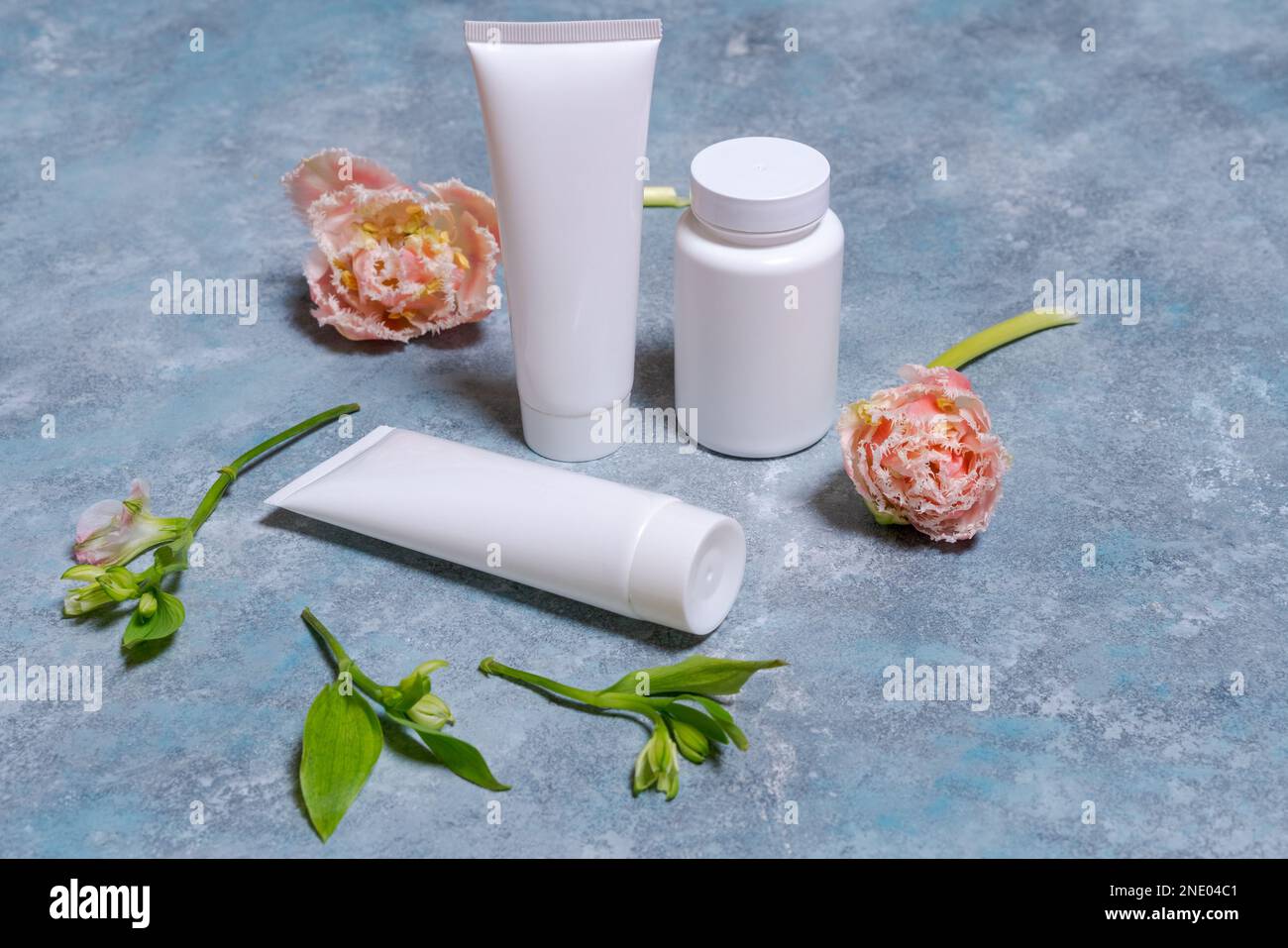 White tube for cream. Branding concept and roses. Tulips on a blue ...