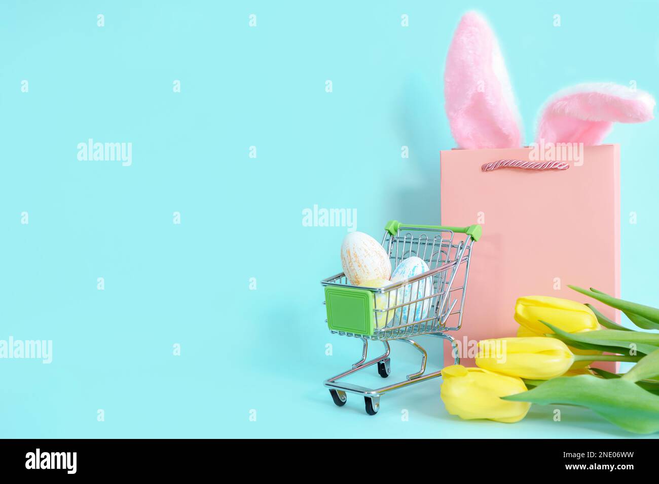 Easter eggs in a grocery basket on a blue background with yellow tulips ...