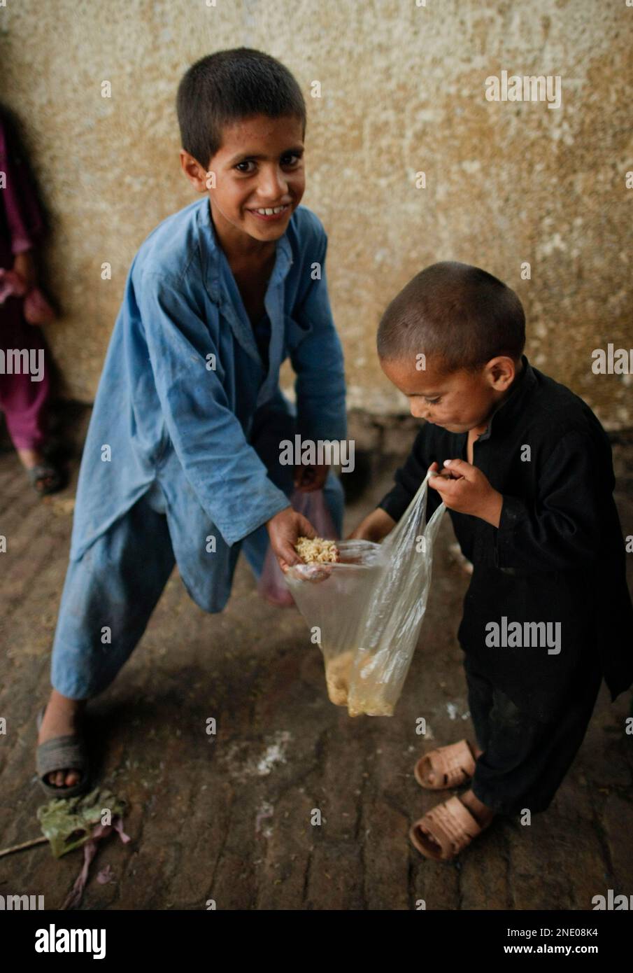 Pakistani children eat dinner at a donated food distribution center at ...