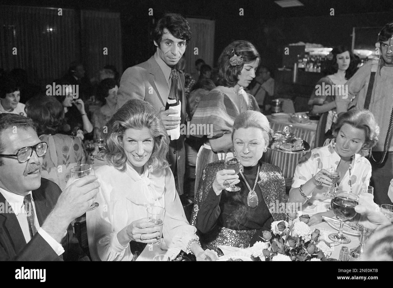 Guests at a dinner in honor of Nancy Kissinger lift glasses for a toast ...