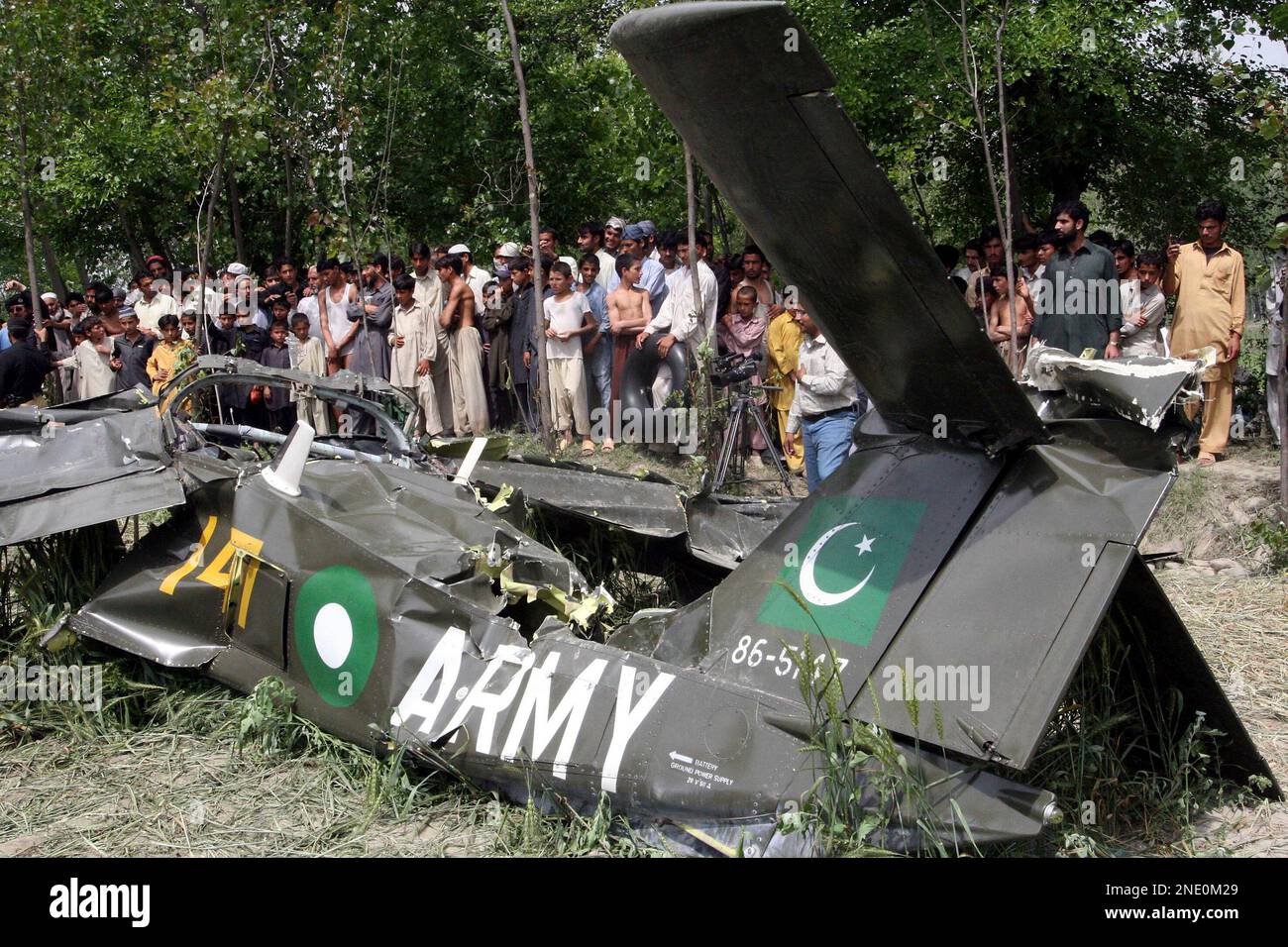 Pakistani villagers surround the wreckage of a Mushak training aircraft ...