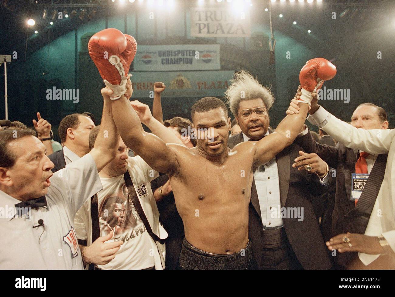 Handlers hold up Mike Tyson?s arms in victory as Don King, right, looks ...
