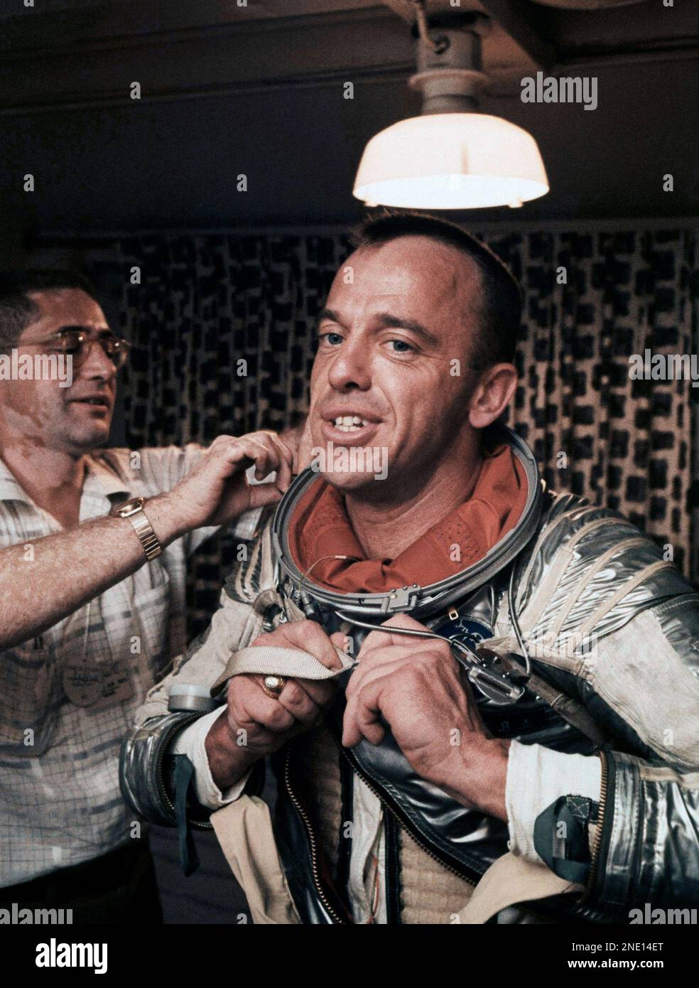 Astronaut Alan Shepard, being helped out to his space suit aboard ...