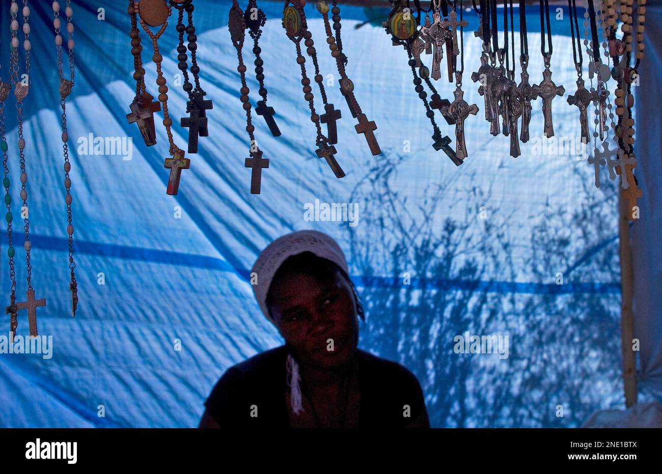 A vendor sits under crucifixes during Holy Week in Ganthier, Haiti ...