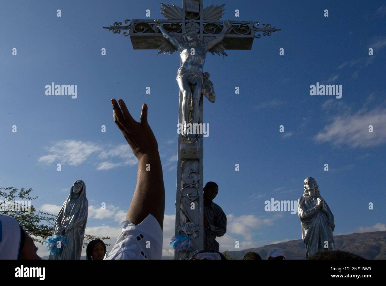 People gestures in front of a cross during a Holy Week procession in ...