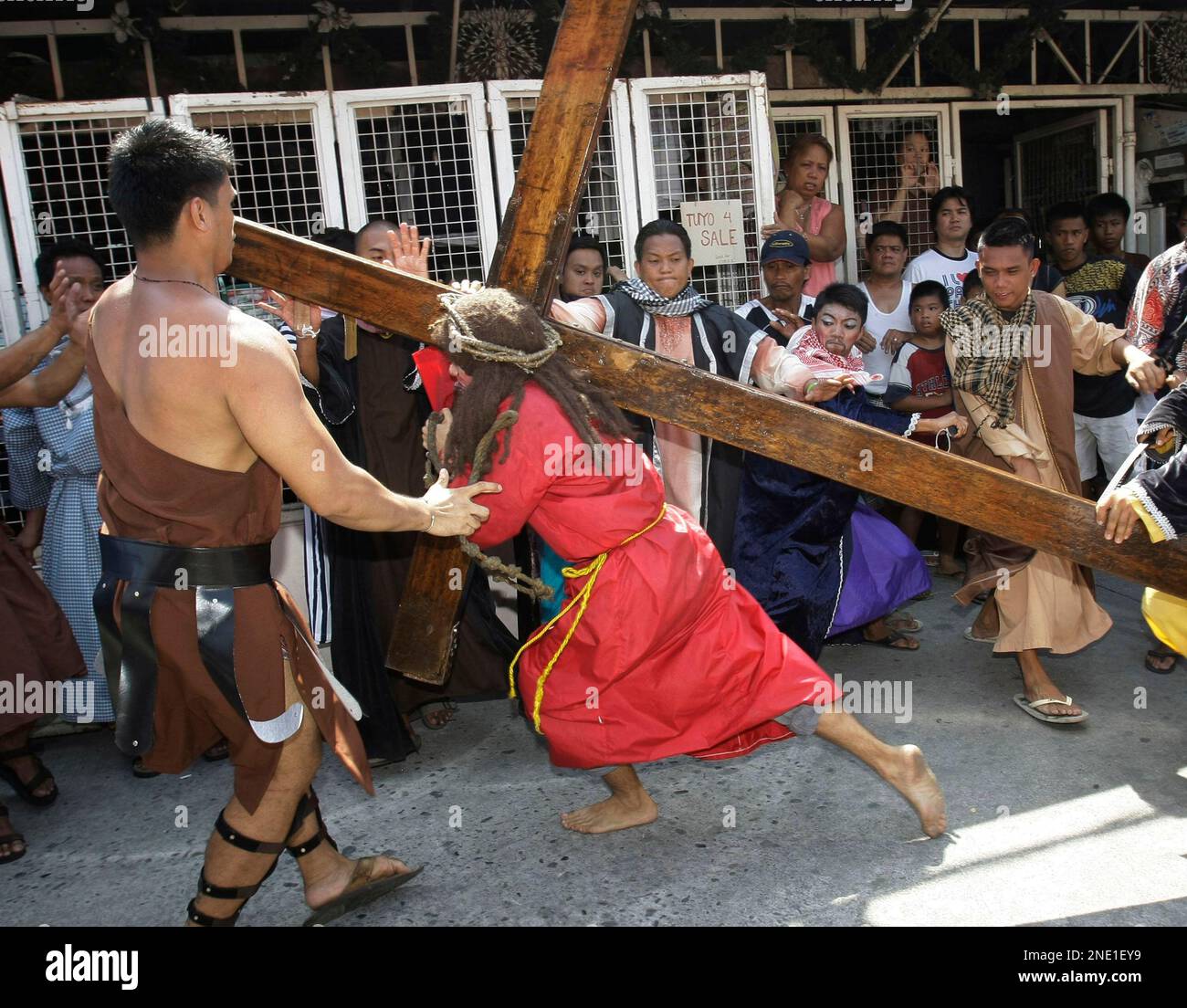 A man rushes forward carrying a cross as he is whipped by others during ...