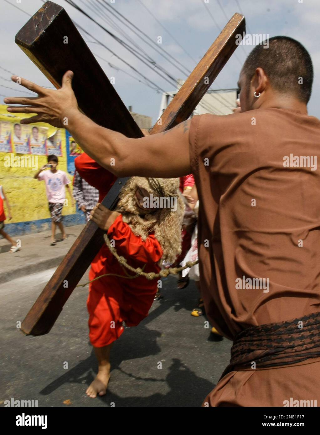 A man reaches out to catch the cross carried by a man during the ...