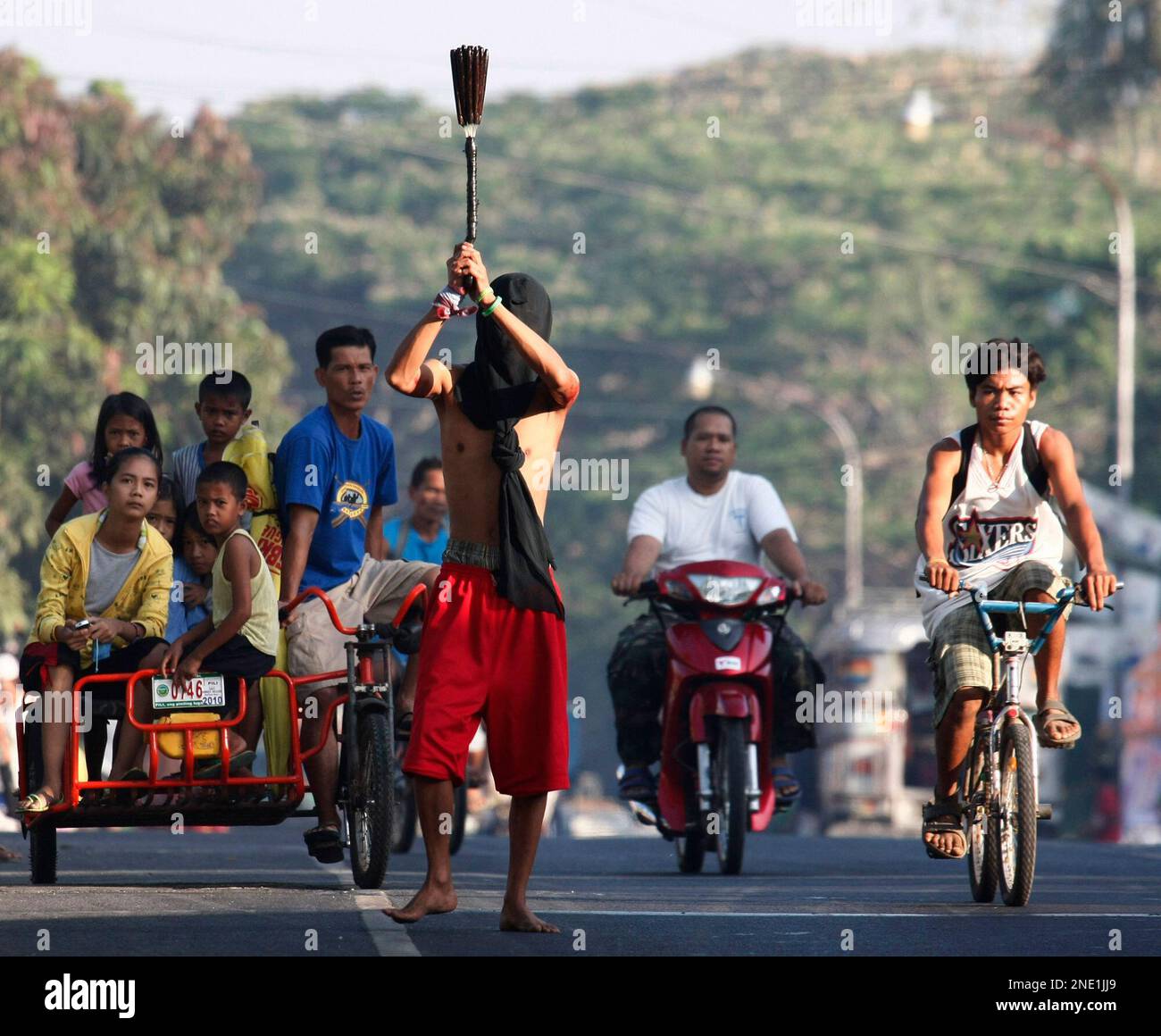 A hooded penitent flagellates himself along a highway to reenact the ...