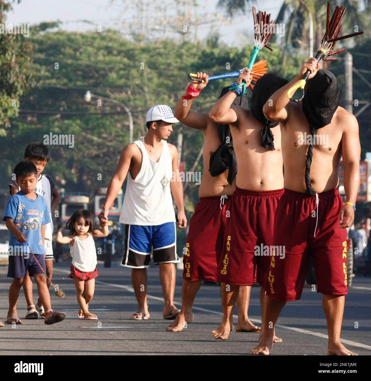Hooded penitents flagellate themselves along a highway to reenact the ...