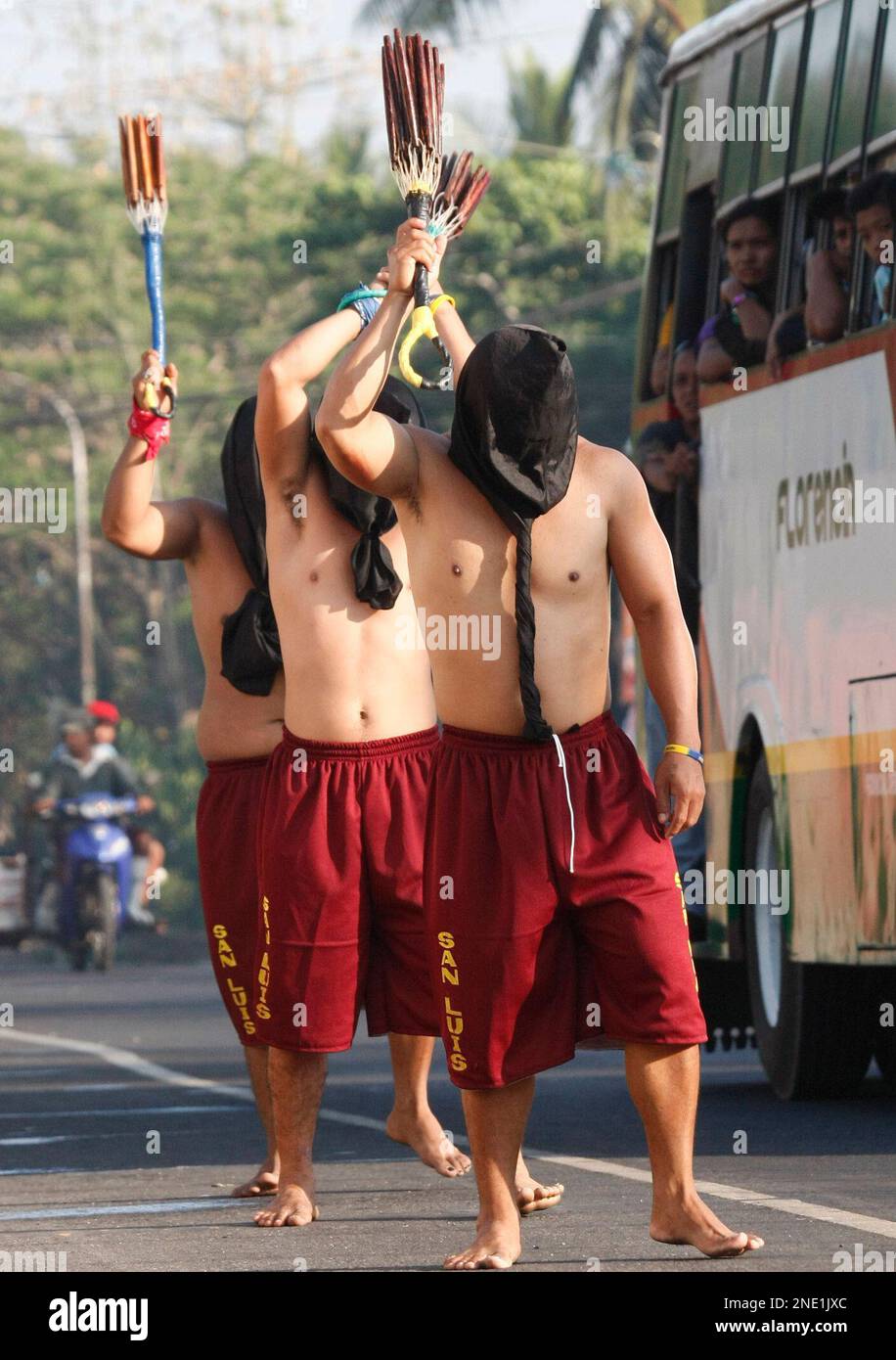 Hooded penitents flagellate themselves along a highway to reenact the ...