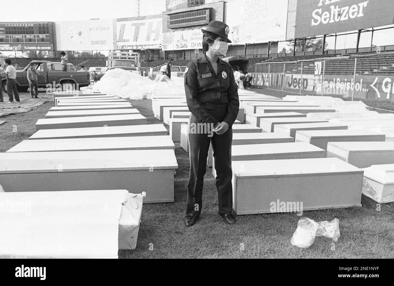 A masked security guard stands watch over coffins at a temporary morgue ...