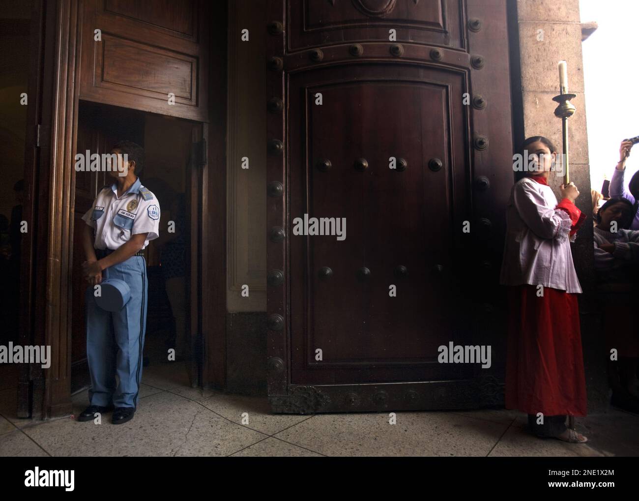A security guard, left, and an altar girl wait at a church prior to a ...