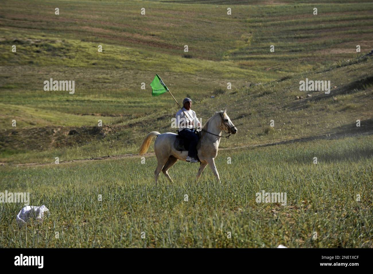 A Bedouin youth holding a flag of the Islamic movement rides his horse ...