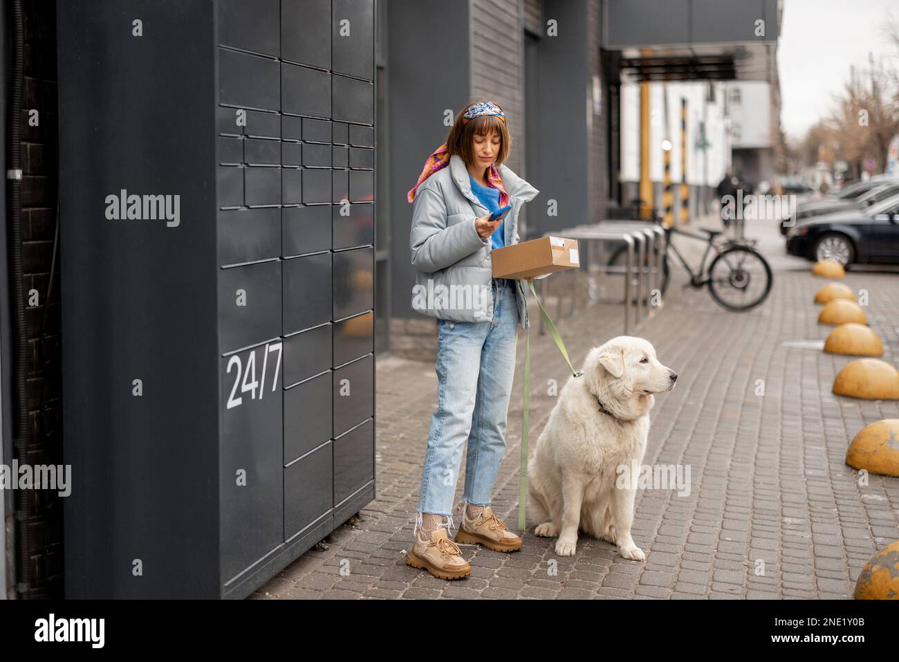 Woman receiving a parcel from automatic post machine during a walk with ...
