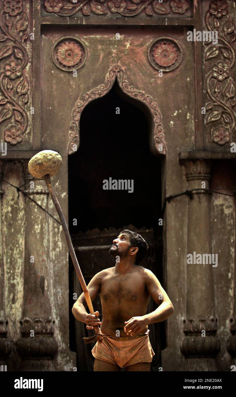 A traditional Indian wrestler exercises with a weight during a practice ...
