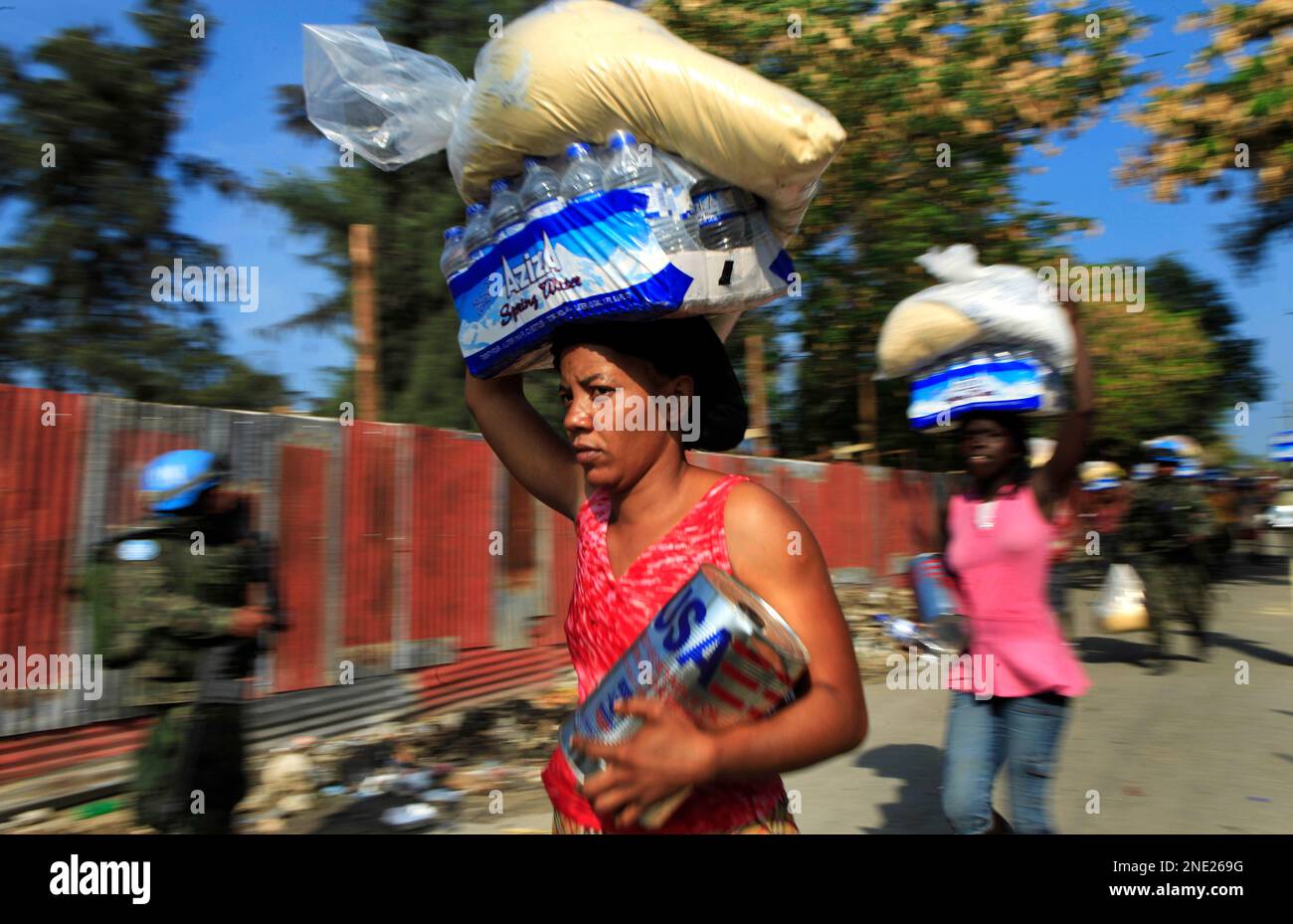 Women carry food aid as UN peacekeepers patrol in Port-au-Prince ...