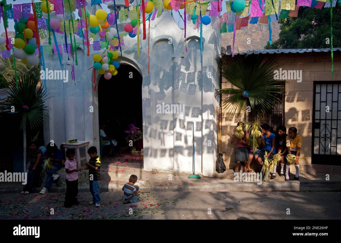 People sit outside a church decorated for Palm Sunday celebrations in ...