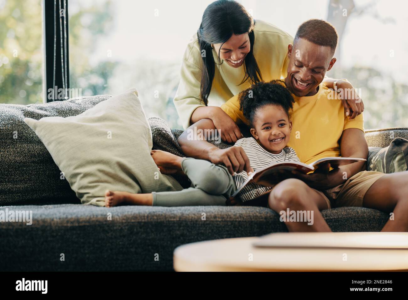 Happy little girl reading a story with her mother and father. Parents ...