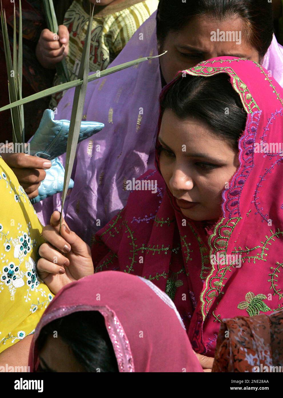 A Pakistani Christian woman holds a palm frond during blessing rites ...