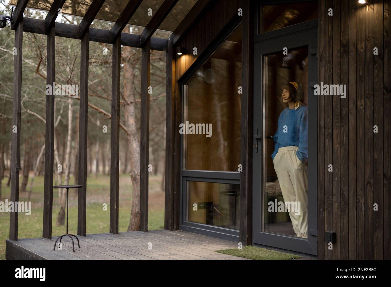 Woman looks out the window at house in nature Stock Photo - Alamy