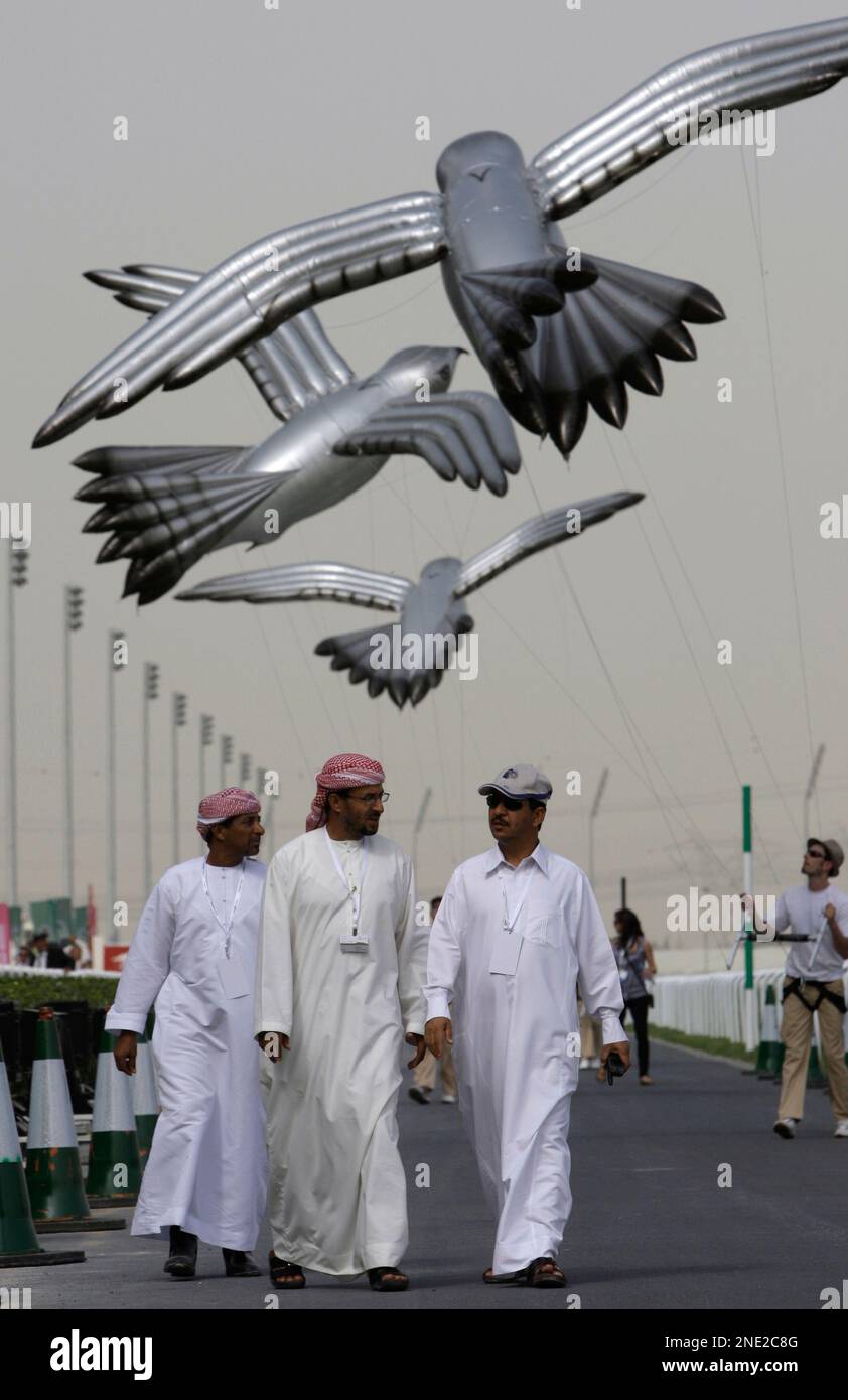 A man flies bird shaped balloons as a few Emiratis pass by, during ...