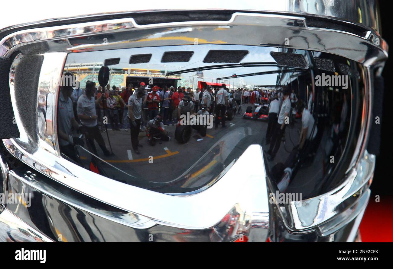 Mechanics for McLaren are reflected in the visor of a team member as ...