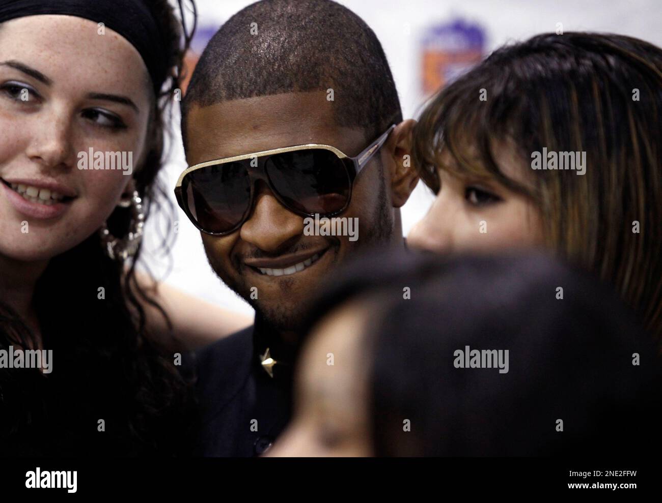 Usher poses for a picture with fans who attended his radio interview as ...
