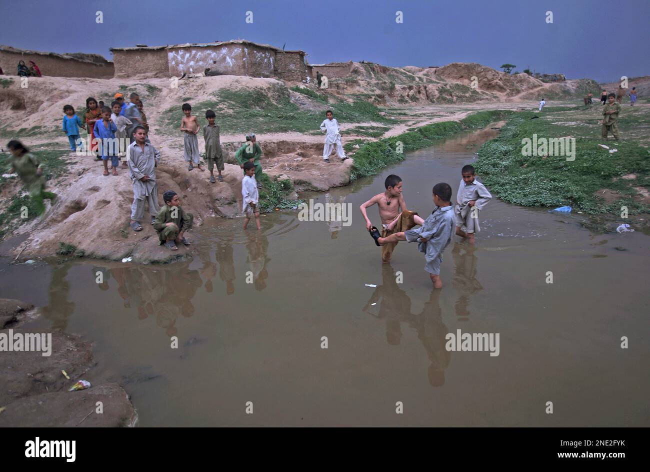 Pakistani and Afghan refugee children play in and around a small river ...
