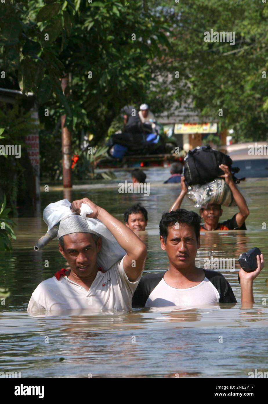 Villagers wade through chest-deep flood water in Karawang, West Java ...