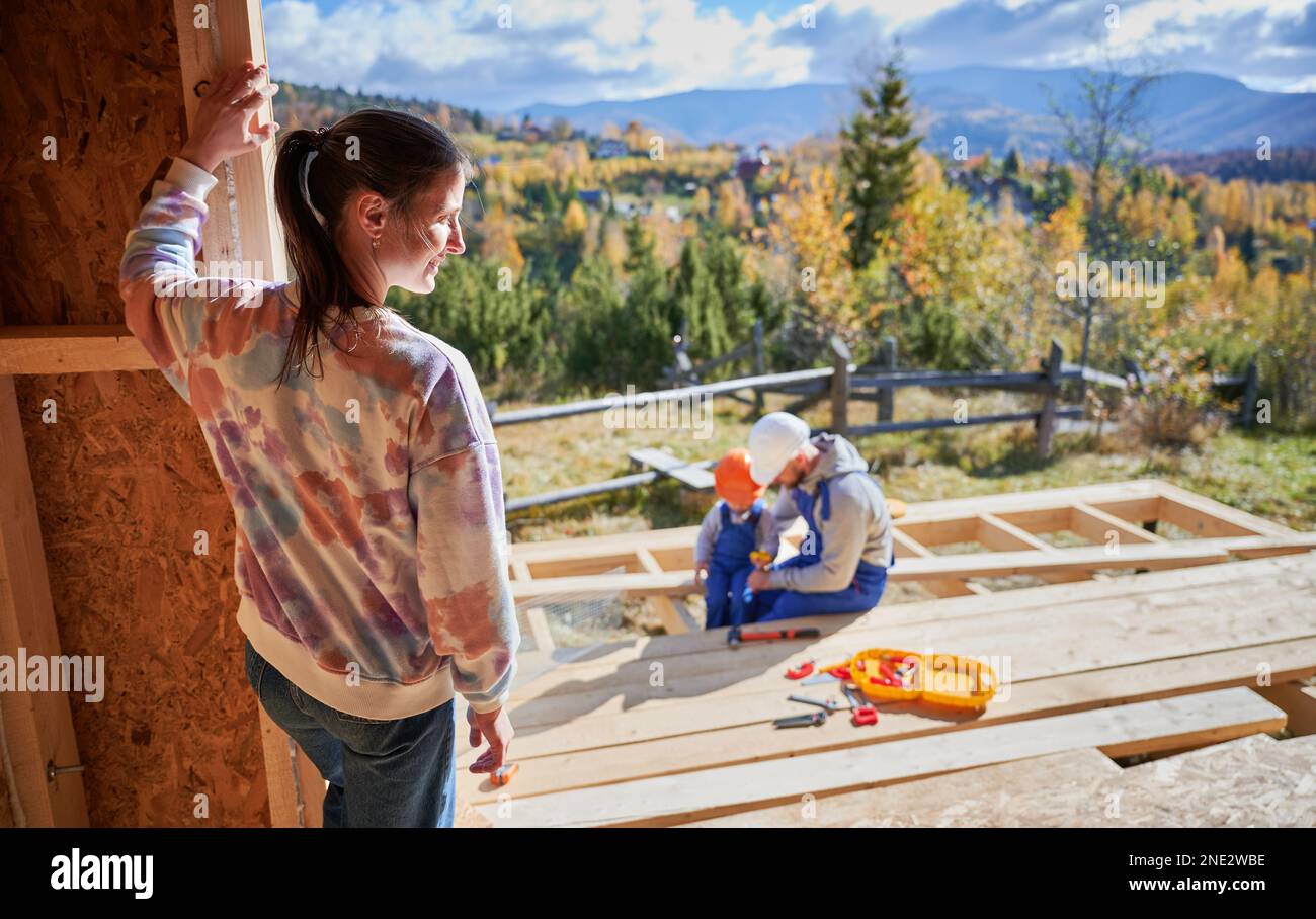 Father, mother and son building wooden frame house. Toddler boy helping ...