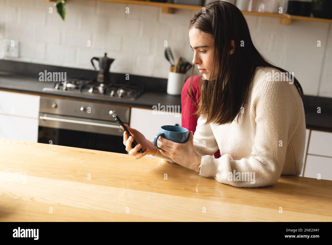 Non-binary trans woman holding a coffee cup using smartphone in the ...