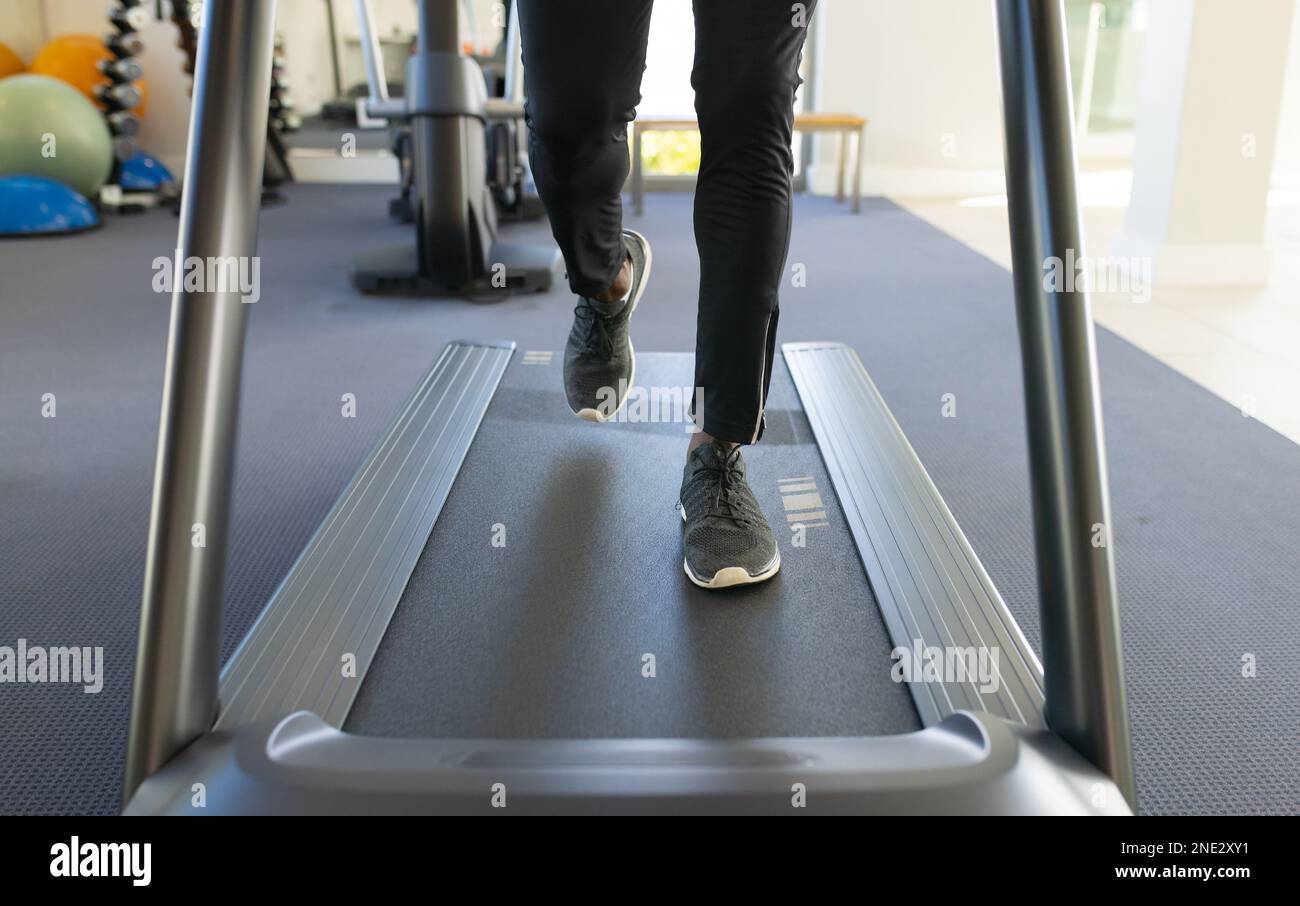 Low section of african american senior man standing on the treadmill at ...