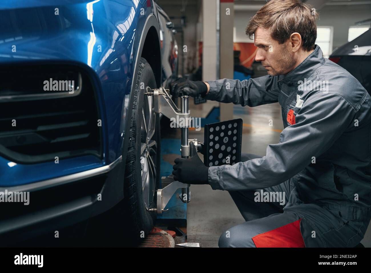 Male inspecting wheel alignment in the workshop Stock Photo - Alamy