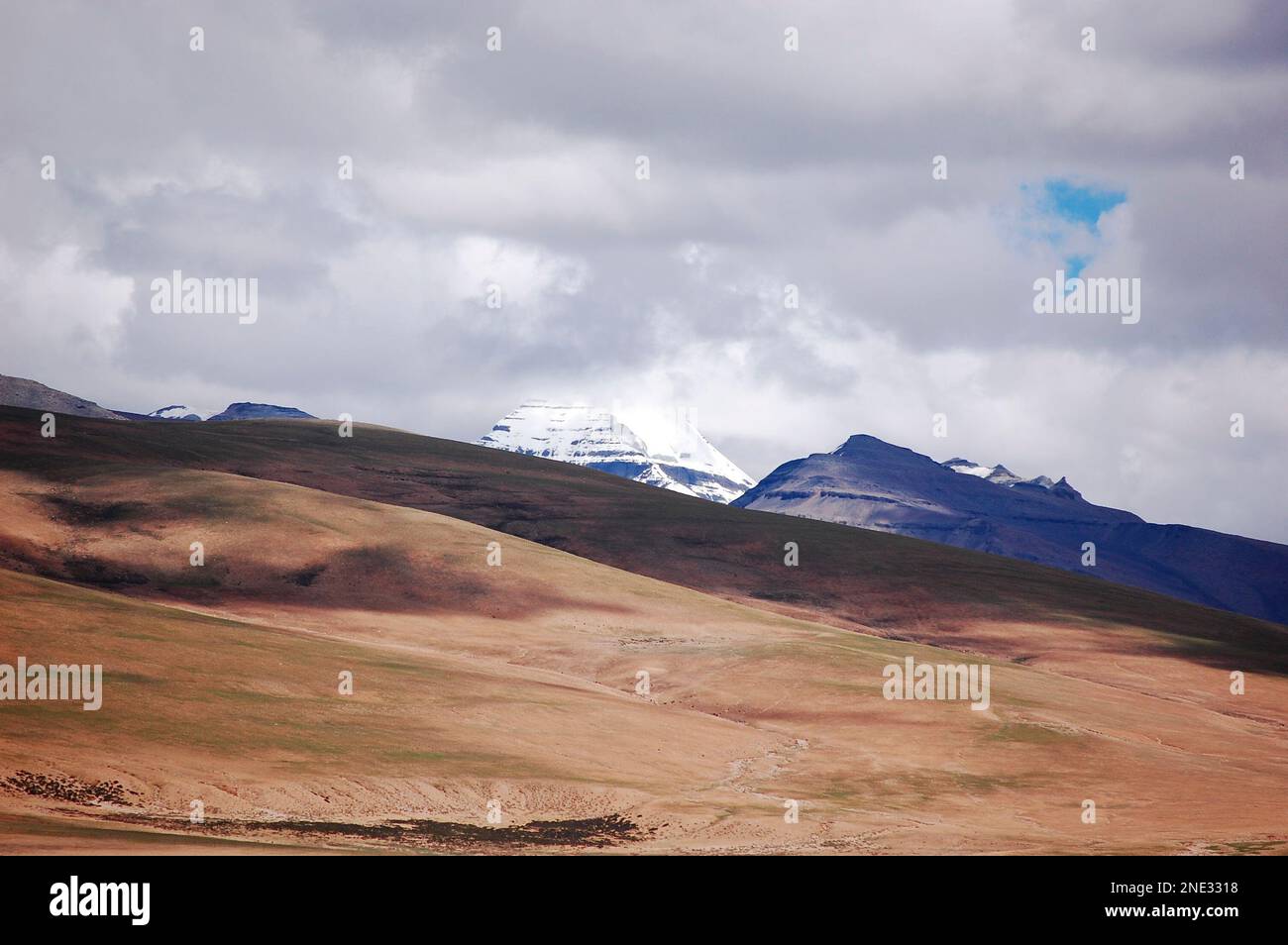 A low-angle of snowy Kangrinboqe peak with a yellow steppe view, cloudy ...